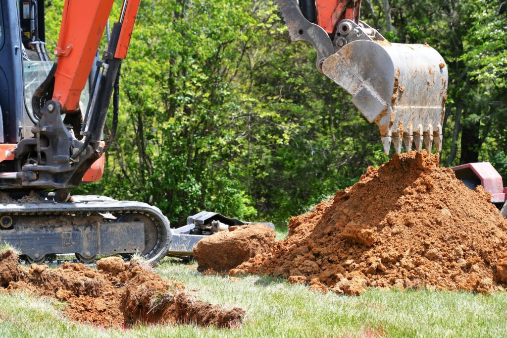 backhoe-digging-dirt-in-a-lawn-to-install-electrical-gas-lines-digging ...